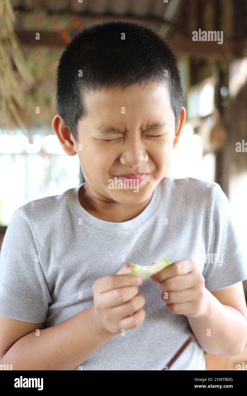 A young boy grimaces after tasting something sour, showcasing a ...