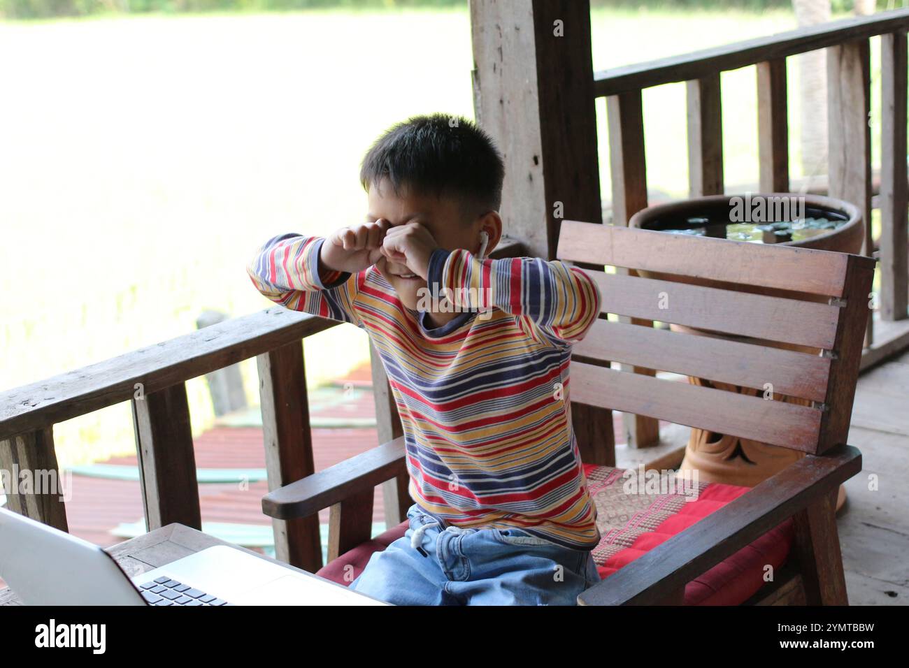 A young child expressing frustration while using a laptop outdoors. The ...