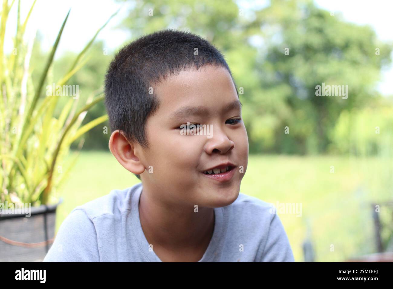 A joyful young boy smiles in a natural outdoor setting, surrounded by ...