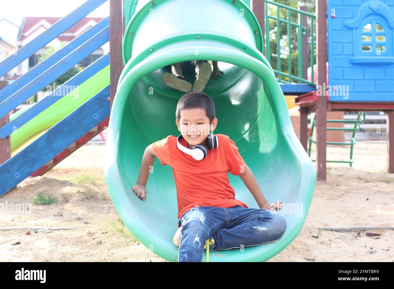 A joyful child slides down a green playground slide, surrounded by ...