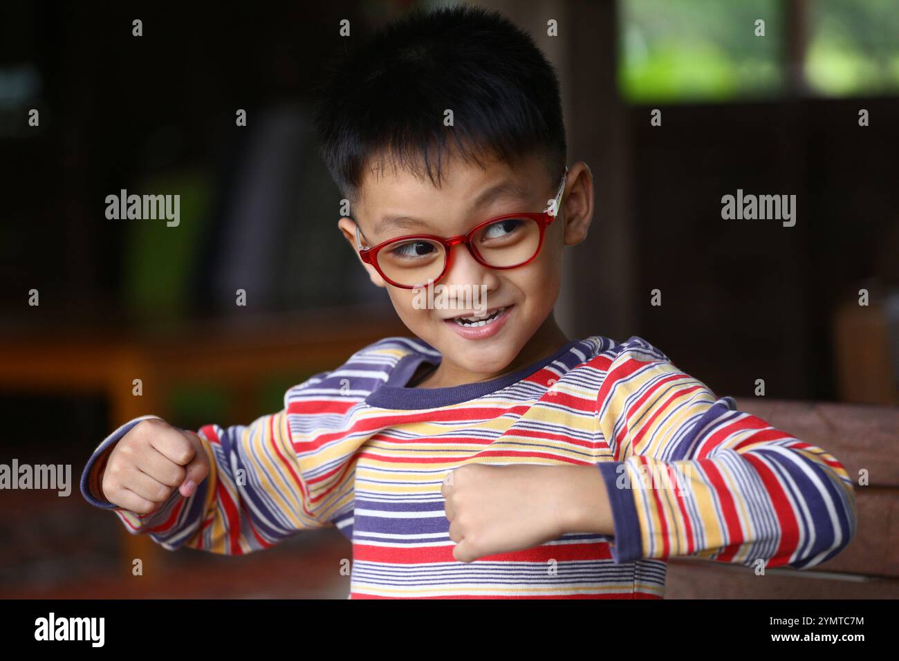 A cheerful child wearing colorful stripes and glasses displays a ...