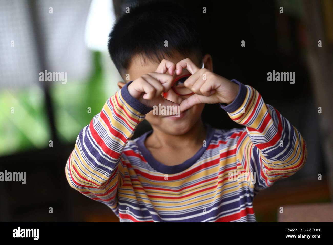 A cheerful child joyfully making a heart shape with hands, showcasing ...