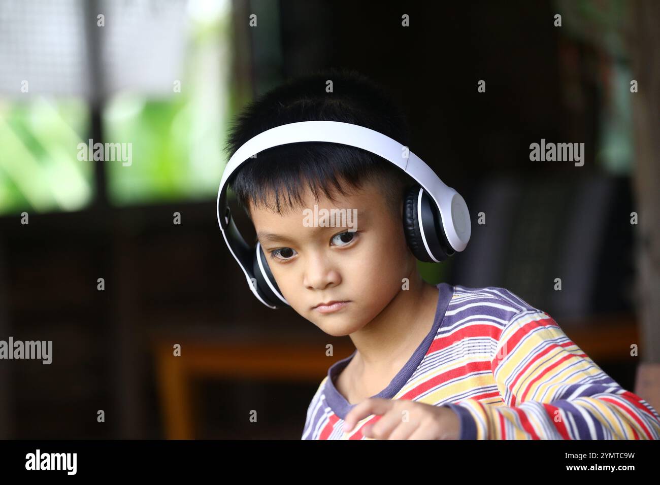 A young boy immersed in music while wearing headphones. His serious ...