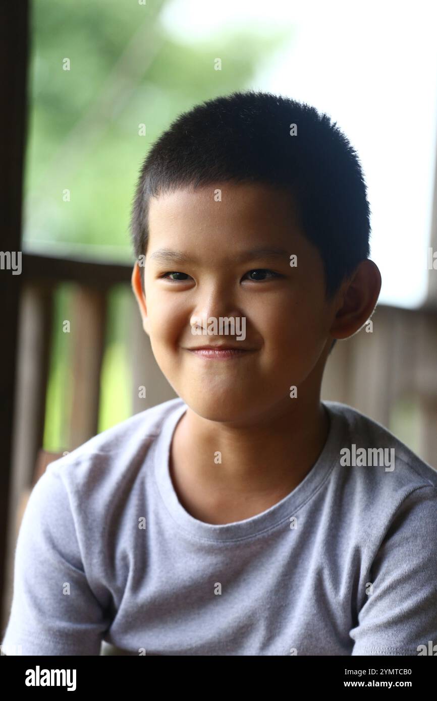 A joyful young boy indoors displays a confident smile, capturing the ...