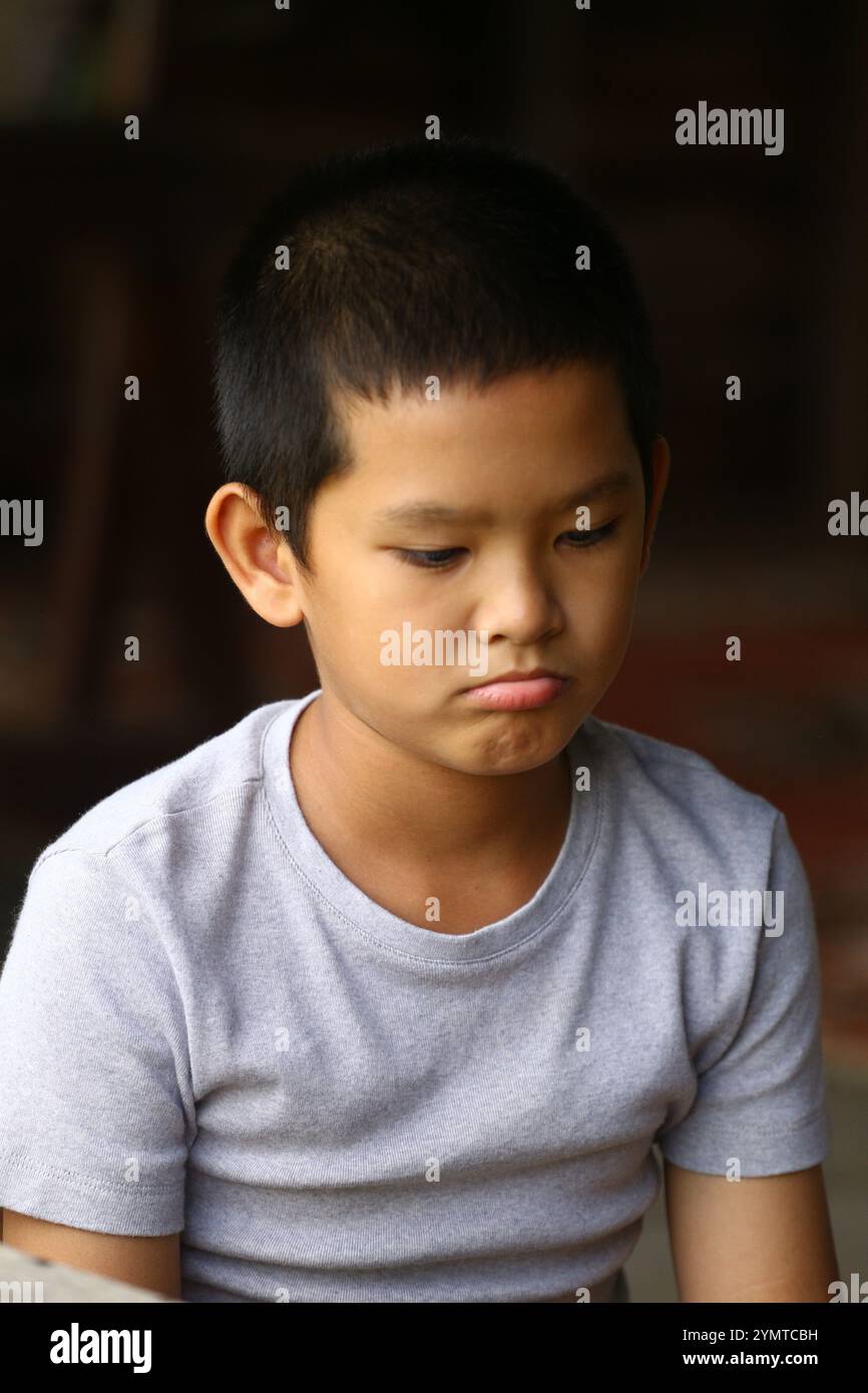 A young boy appears thoughtful and pensive, expressing a mix of ...