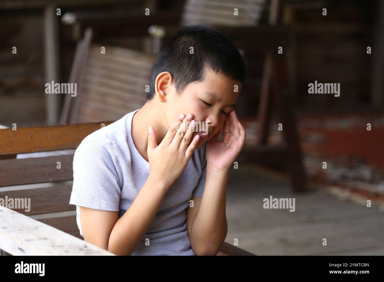 A young boy sitting quietly, lost in thought. His expression reflects a ...