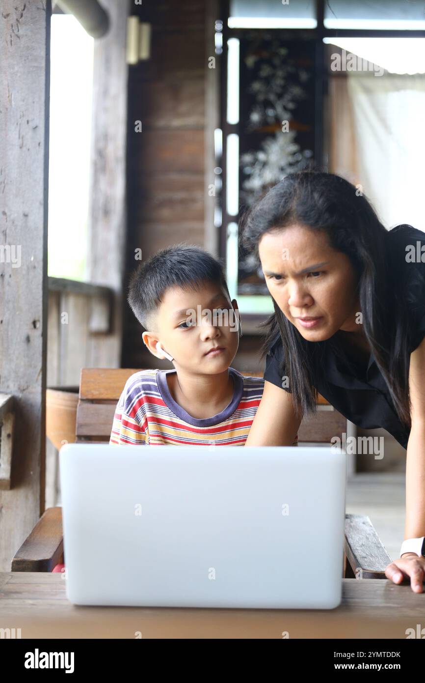 A mother and her child engage with a laptop, immersed in learning at ...