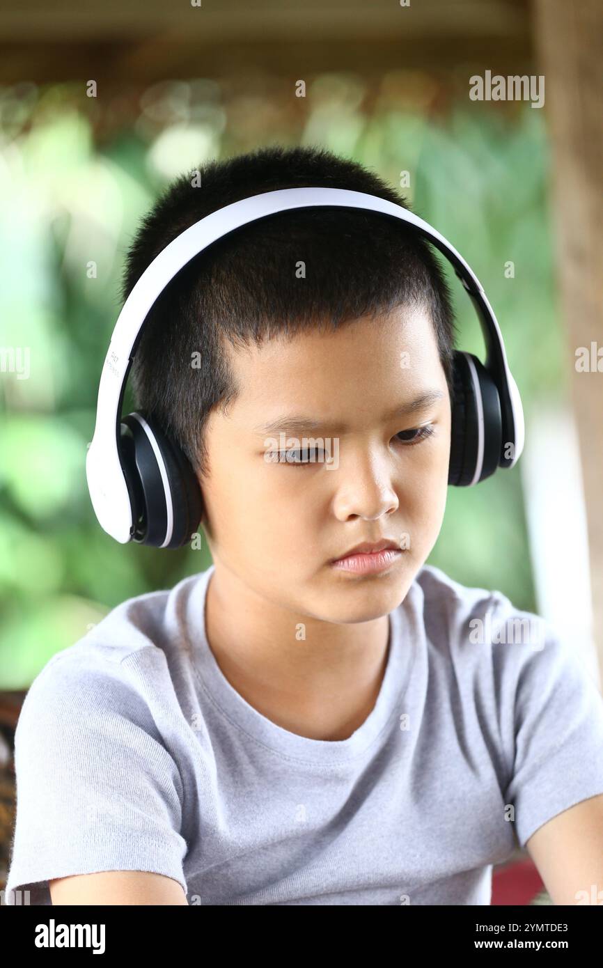 A young boy wearing headphones looks deeply focused while listening to ...