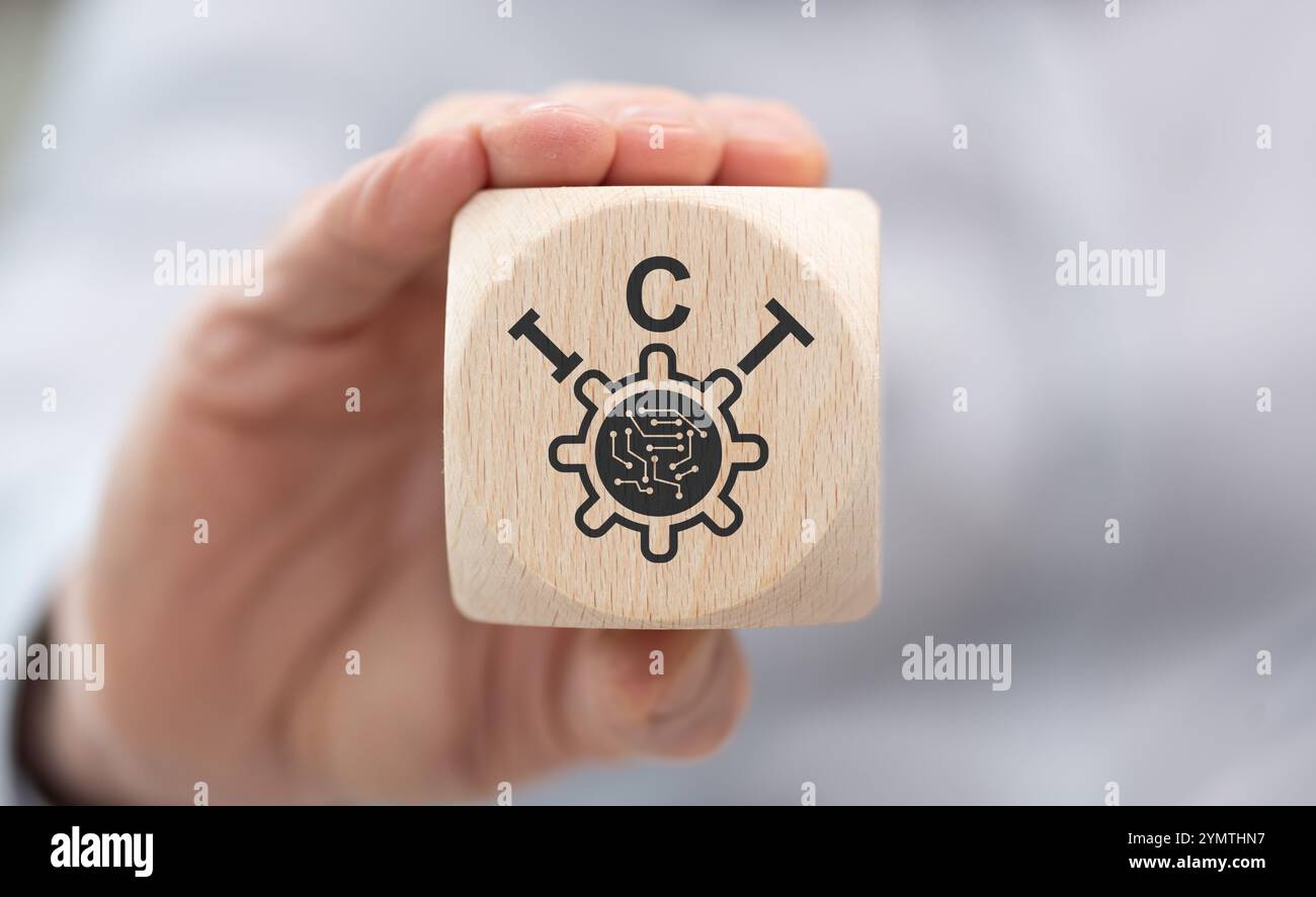 Hand holding a wooden cube with symbol of ict concept Stock Photo - Alamy
