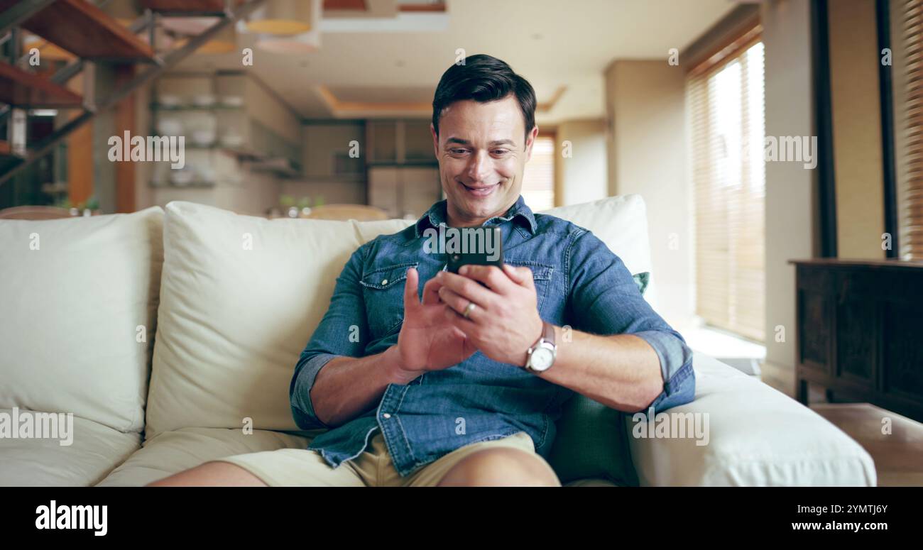Sofa, man and happy with smartphone for chat, conversation and text ...