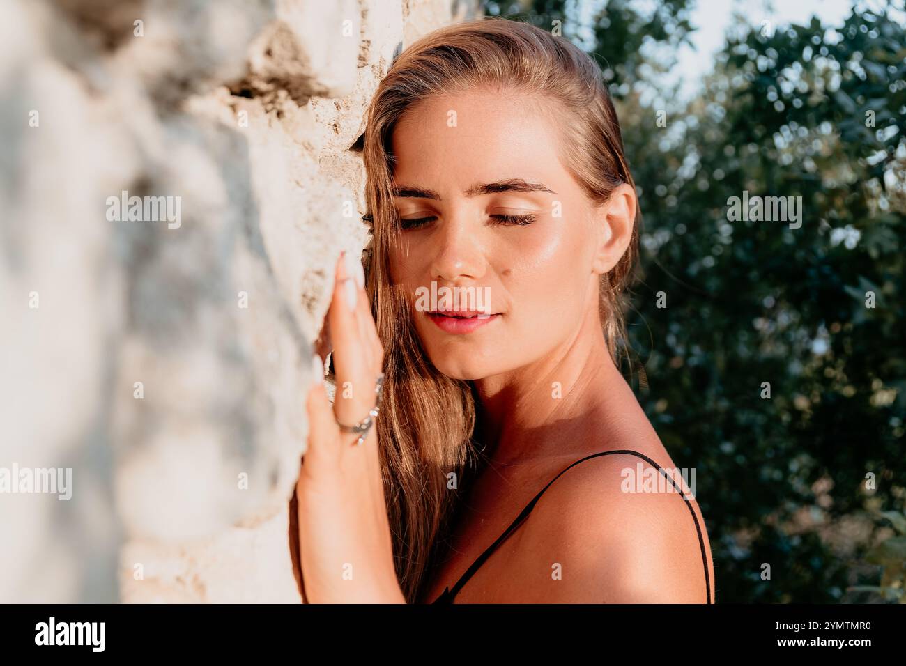 Woman, Wall, Sunlight - A woman with her eyes closed stands against a ...