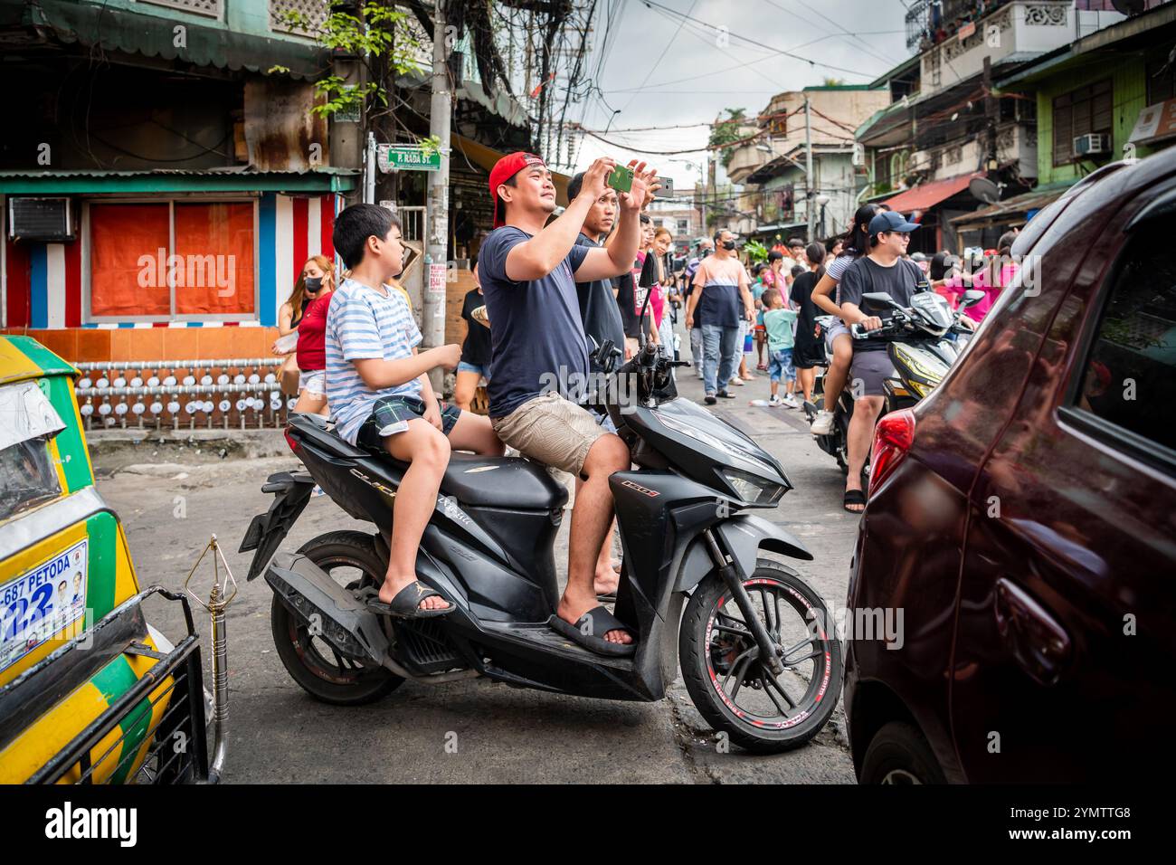 A young Filipino boy gets a ride on the back of a motorbike through the ...