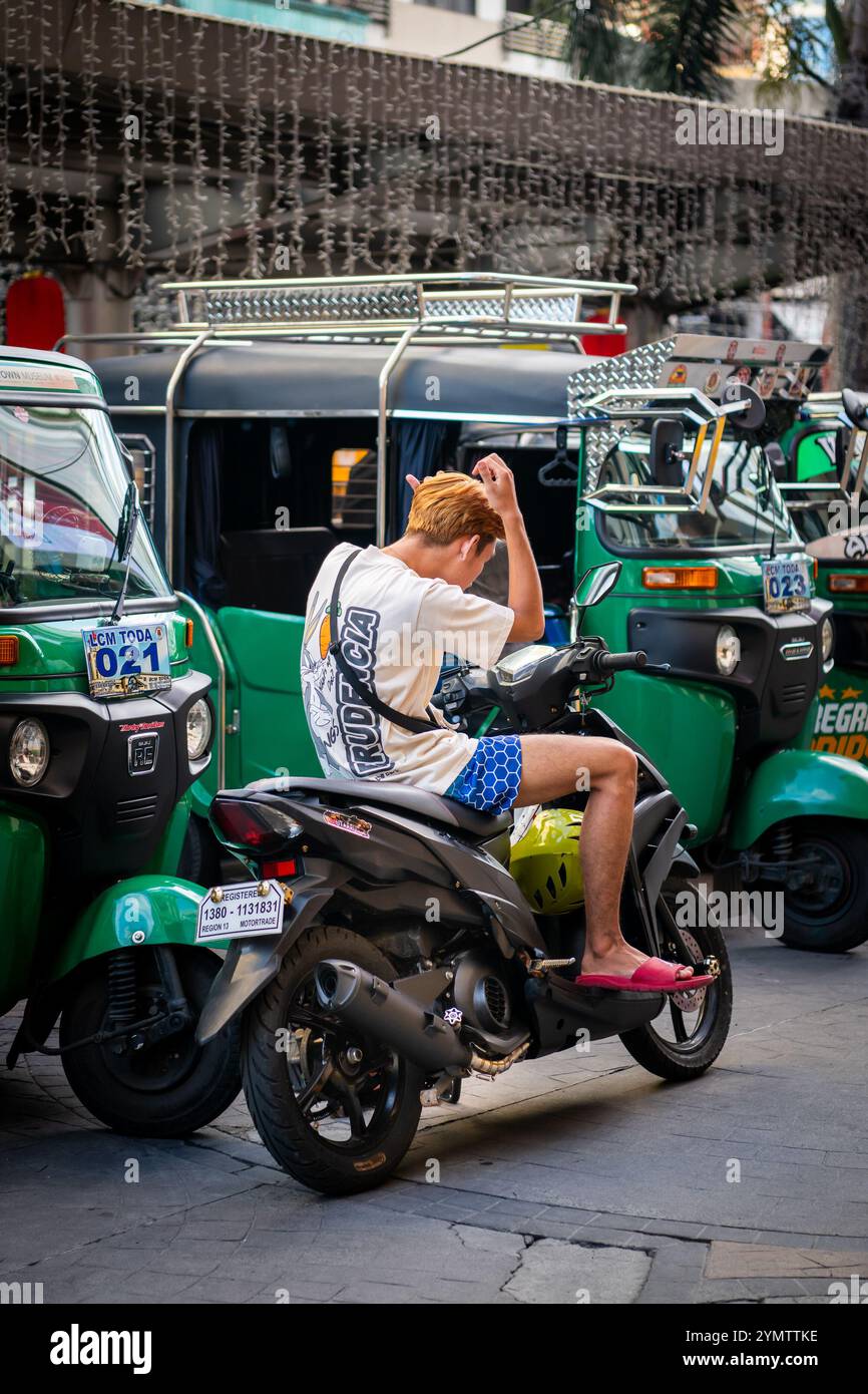 A handsome young Filipino boy checks his hair in the mirror sat on his ...