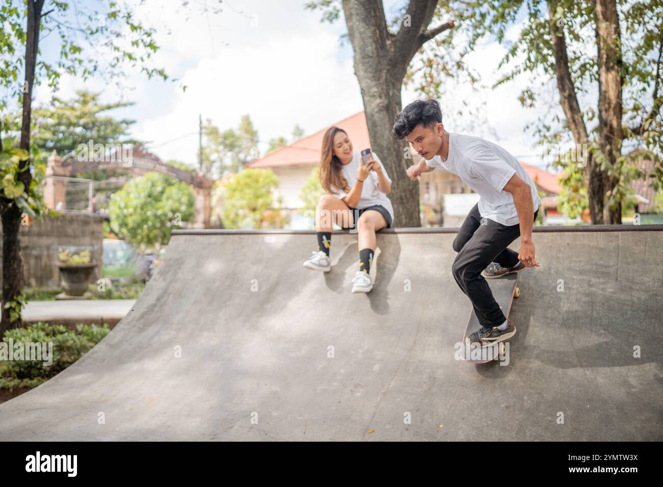 Engaging in dynamic skateboarding action at a sunny park ramp while ...