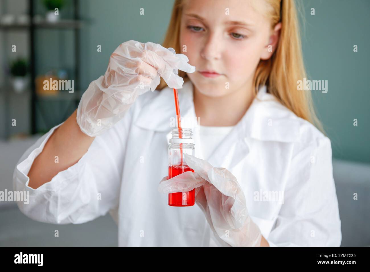 The girl conducts chemical experiments at home. Focus on flasks with ...