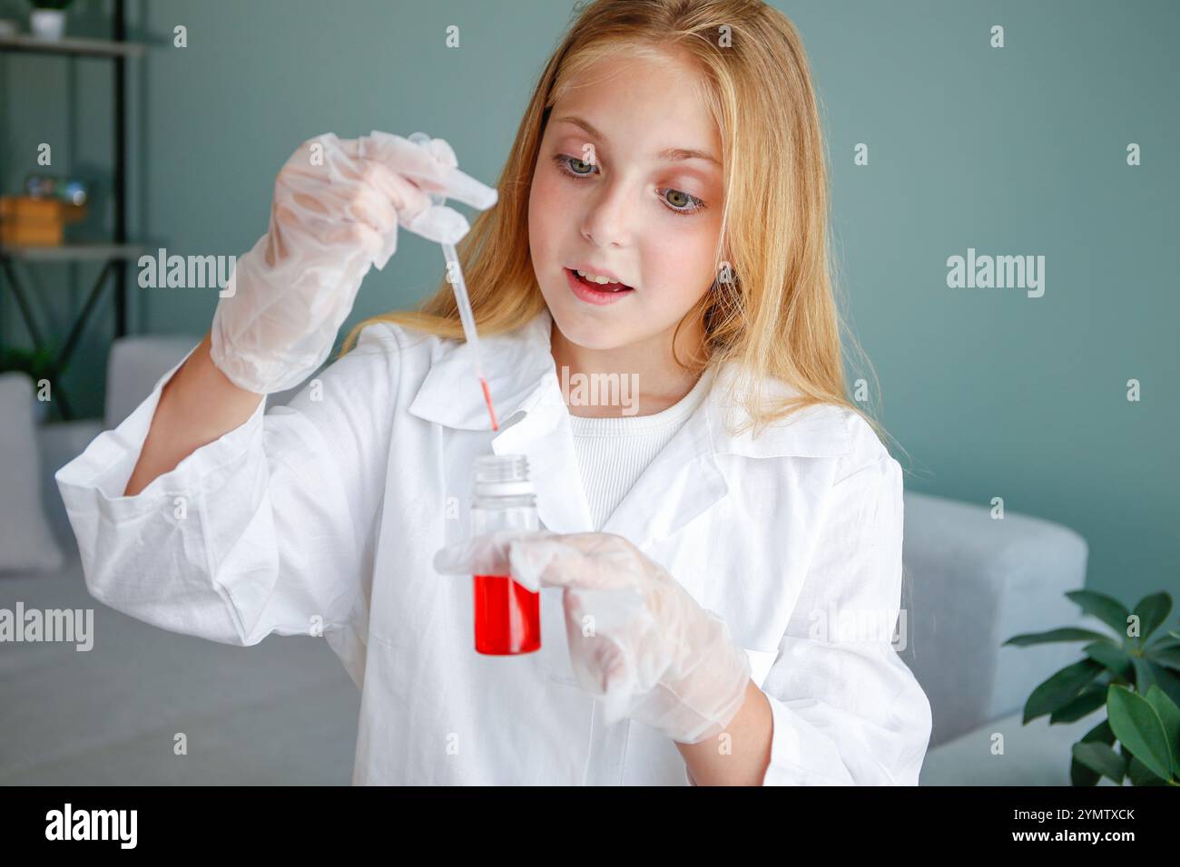 The girl conducts chemical experiments at home. The child is surprised ...