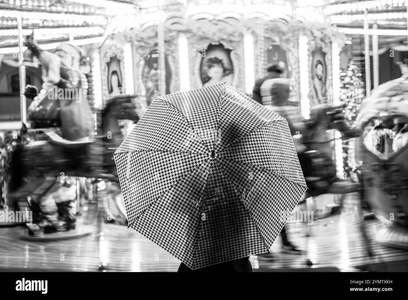 Black and white photo of woman holding umbrella infront of rotating ...