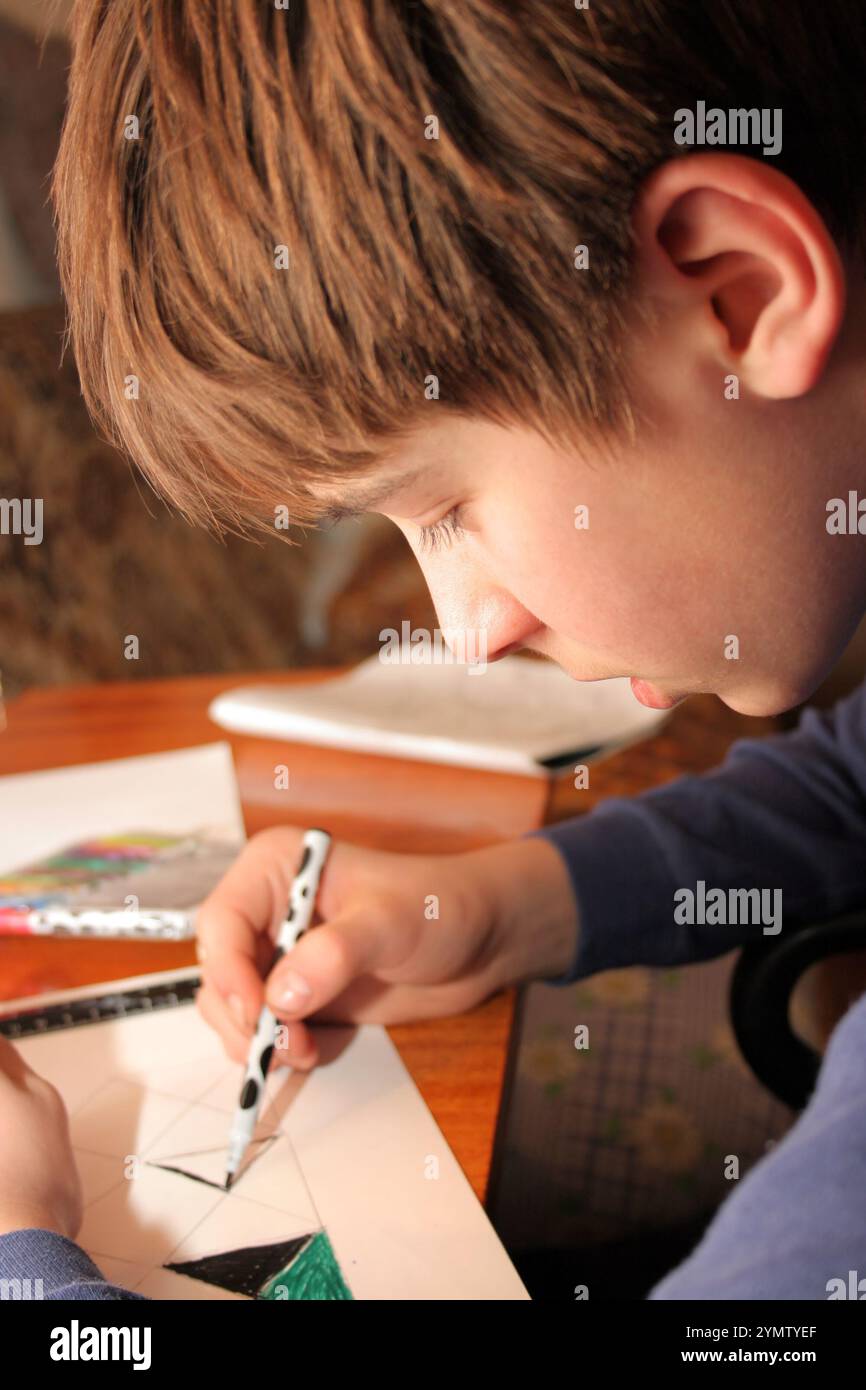 The boy doing lessons and with concentration drawing Stock Photo - Alamy