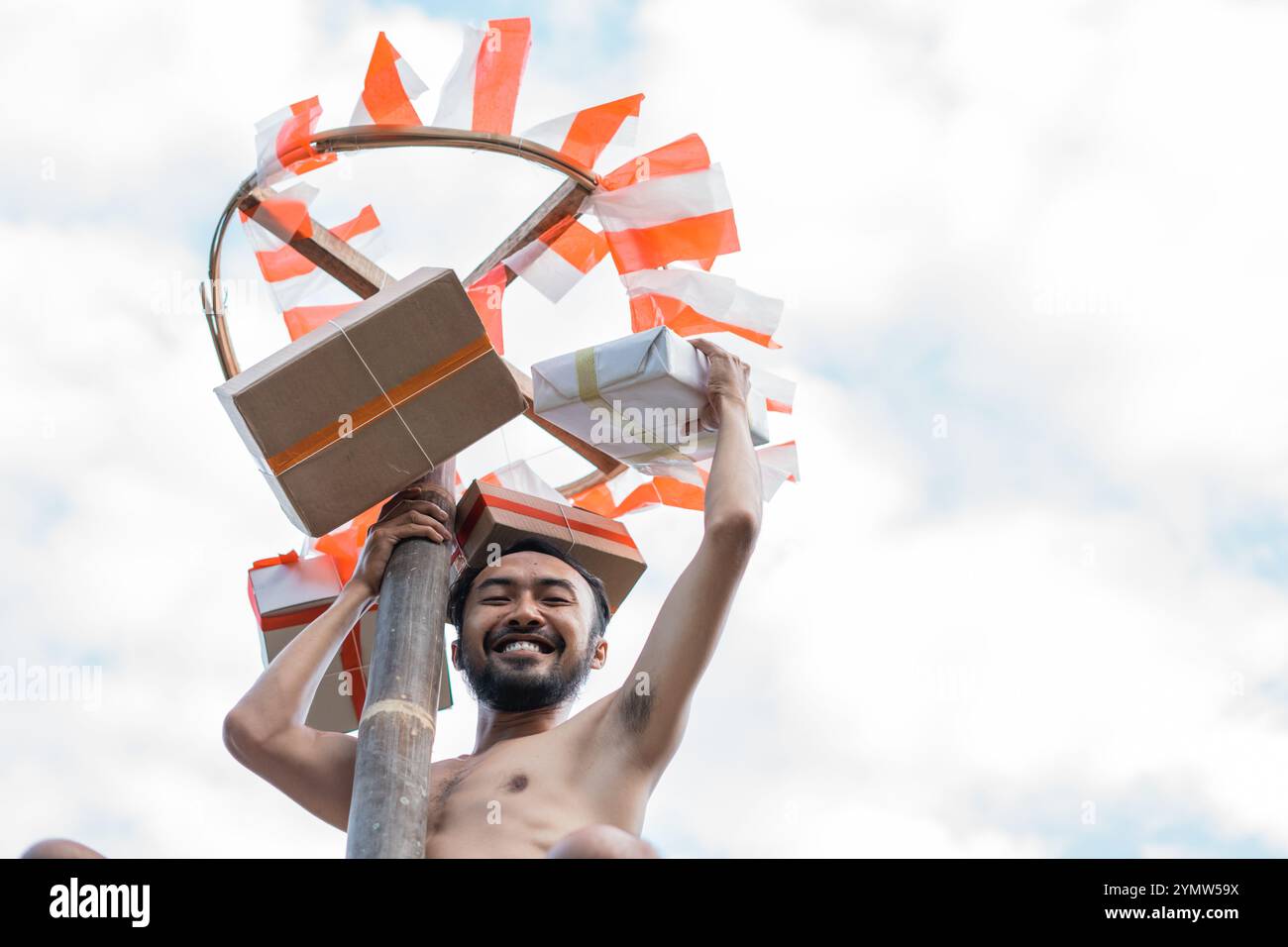 smiling man reaching for the prize box in a betel nut climbing Stock ...
