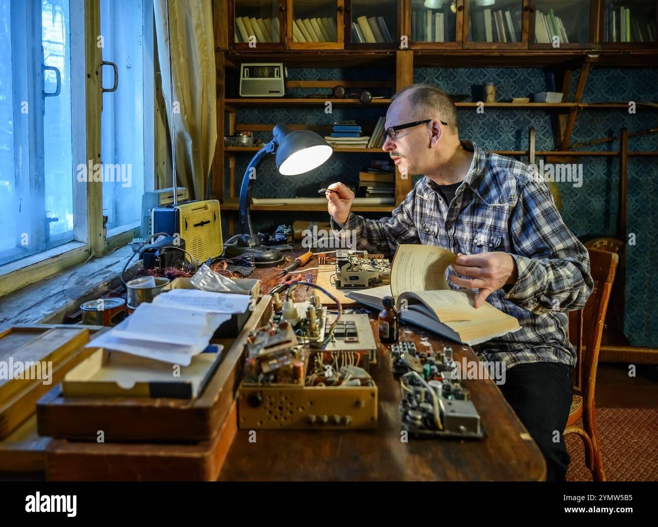 Radio amateur engaged in the repair of a radio receiver. On the table ...