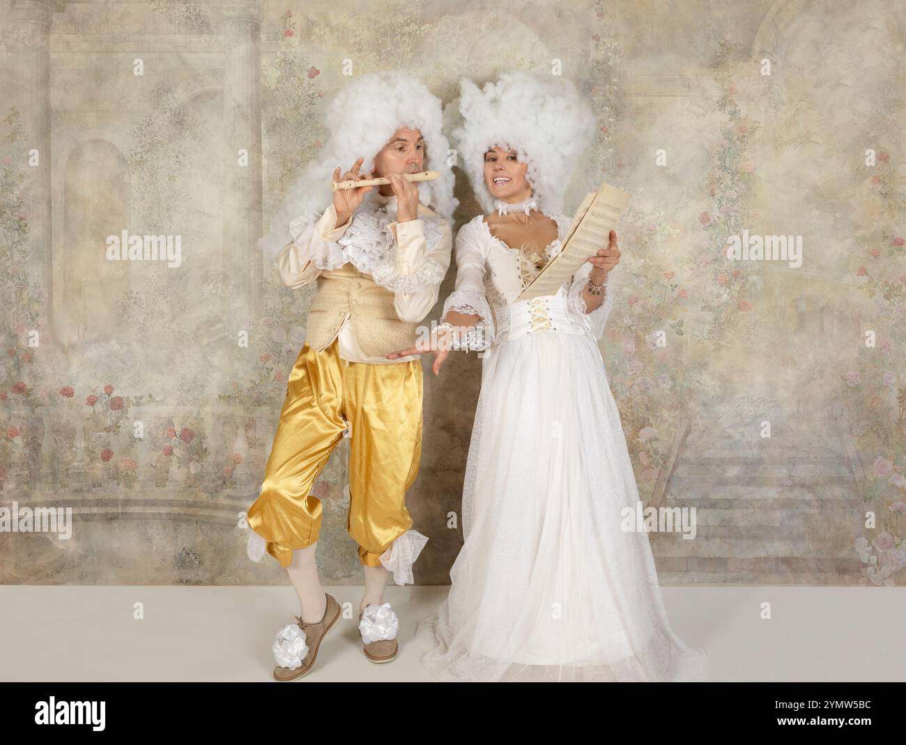 Fun couple in white wigs and Baroque style clothes, a man playing a ...