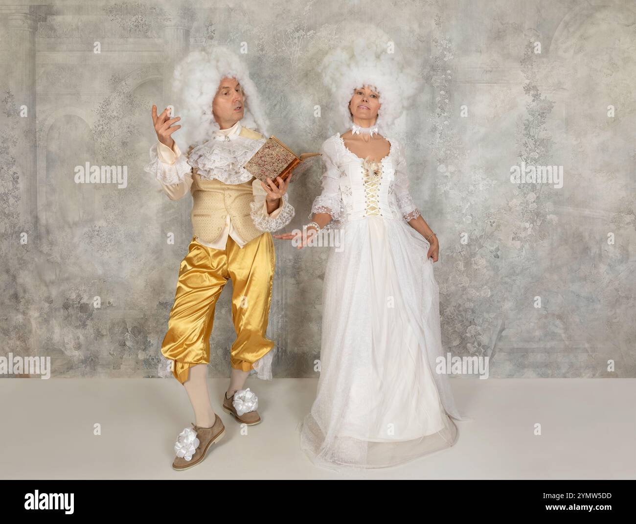Cute couple in Baroque style clothes and white wigs reading a book ...