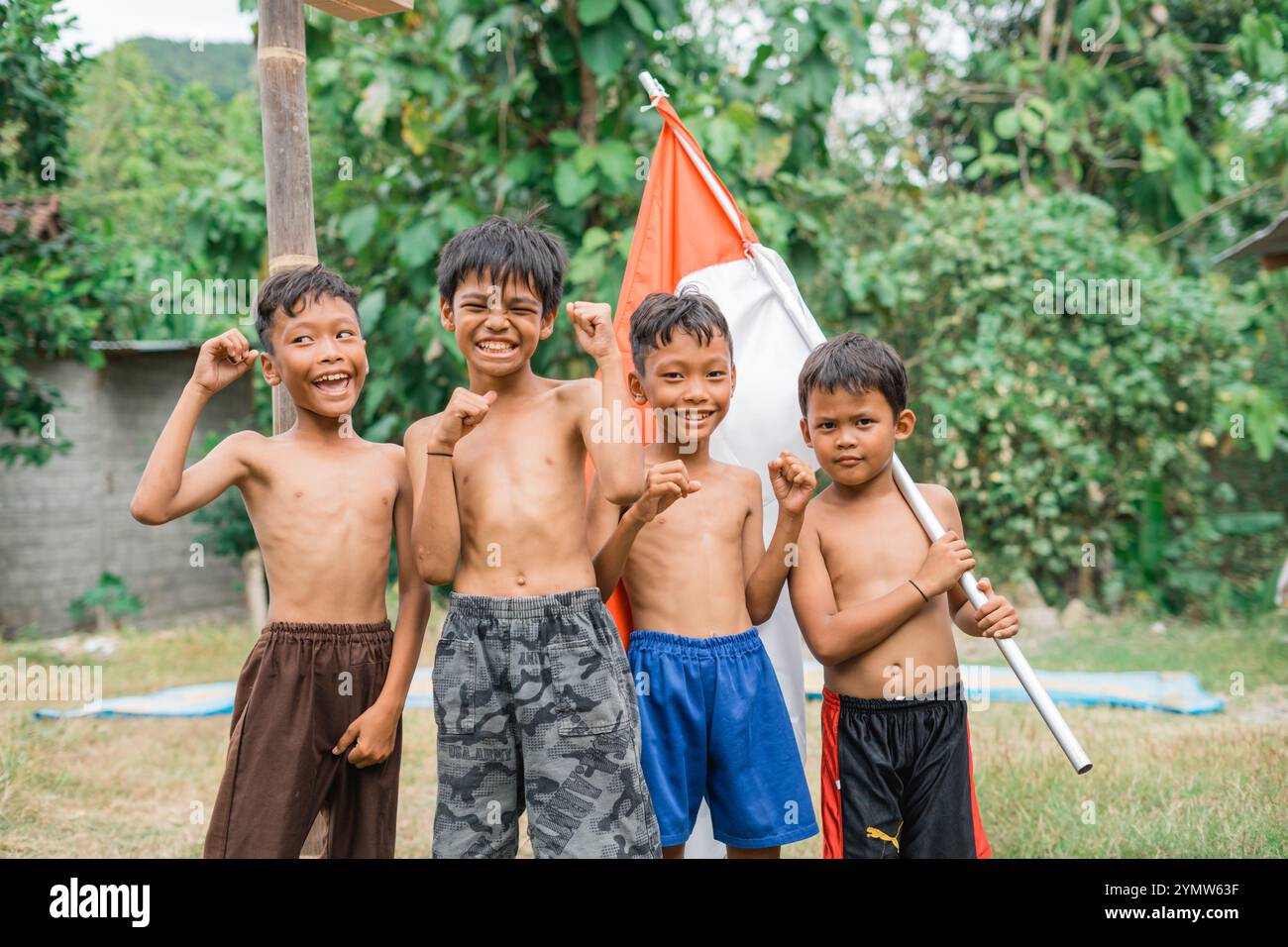 four excited Javanese children make a fist while carrying an Indonesian ...