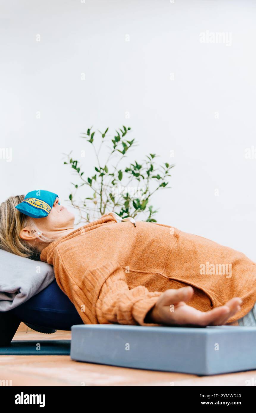 Woman in a cosy yin, restorative yoga pose setup on a terrace Stock ...