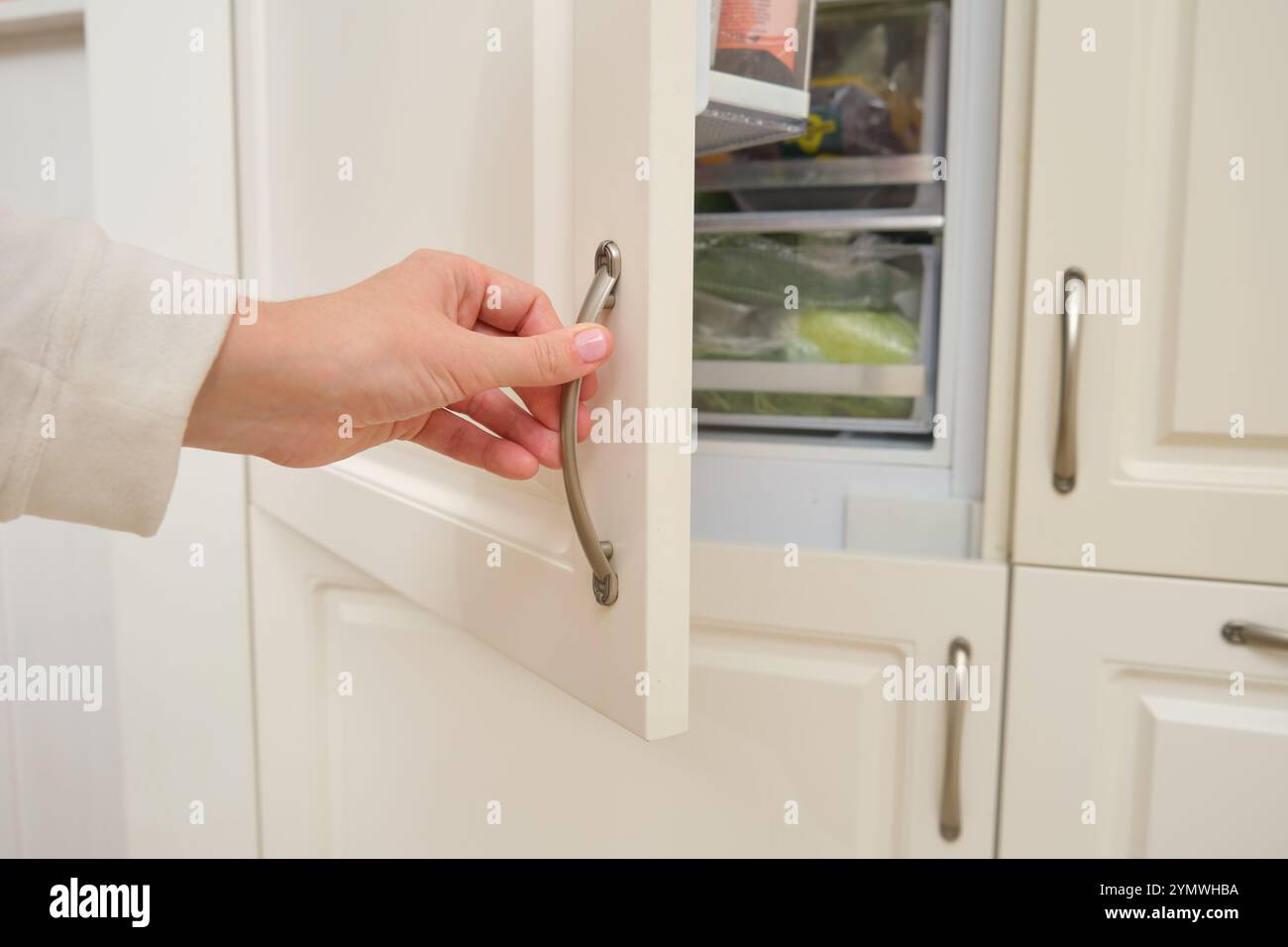 Hand opening refrigerator door with visible food items inside. Close-up ...