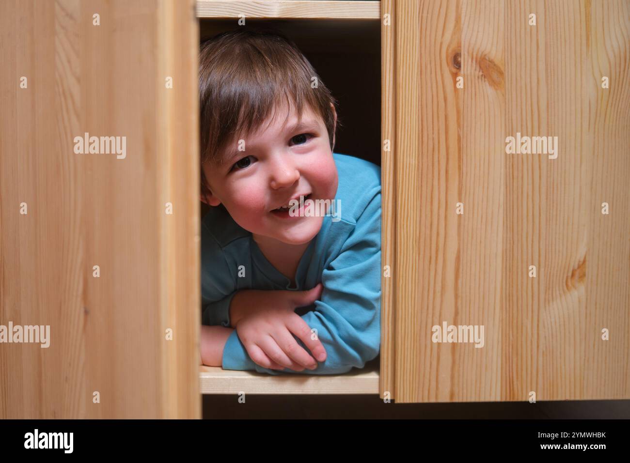 The child is tucked away inside the wardrobe, enjoying a playful game ...