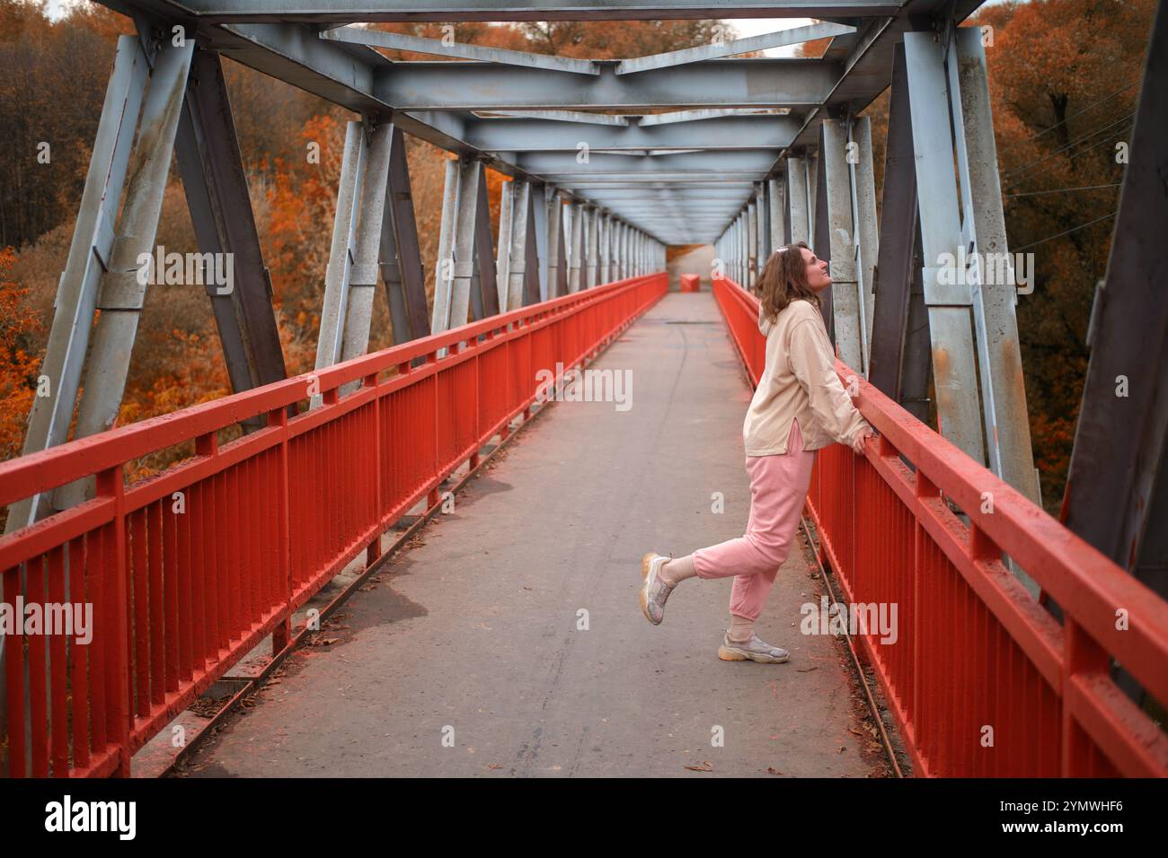 Adult female poses on the concrete bridge, with metal beams towering ...