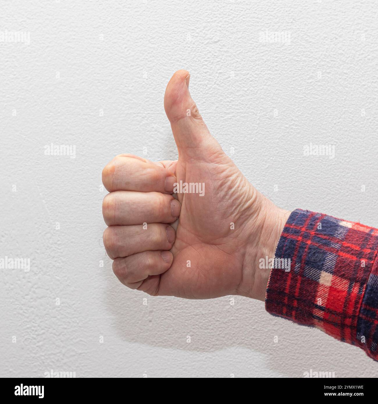 A man's hand clad in a red plaid shirt giving a thumbs up against a ...