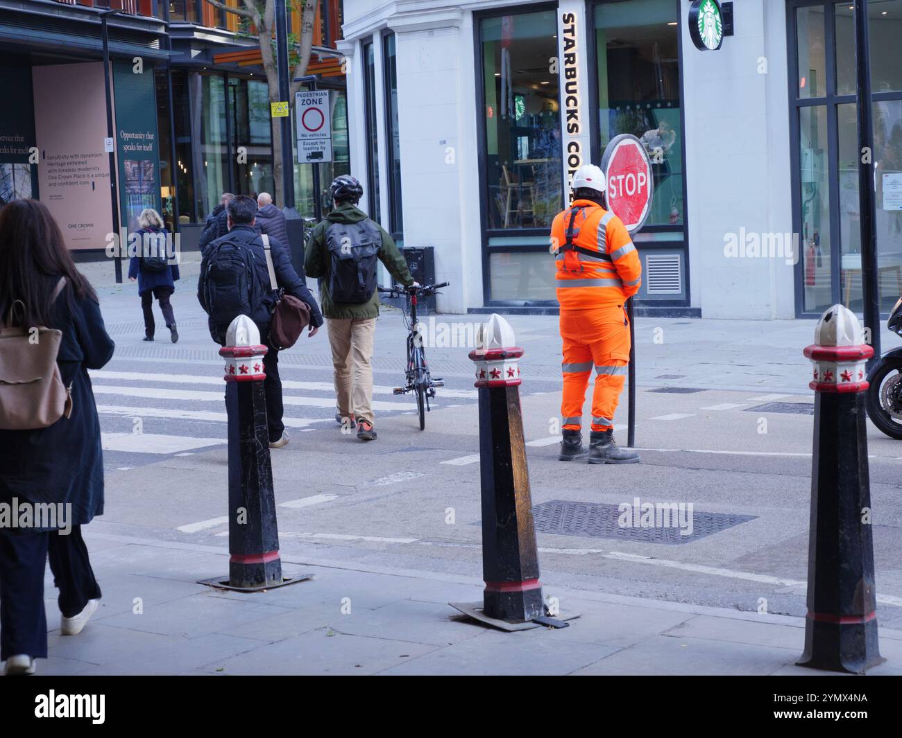 Banksman with stop traffic sign directing pedestrians and traffic at ...