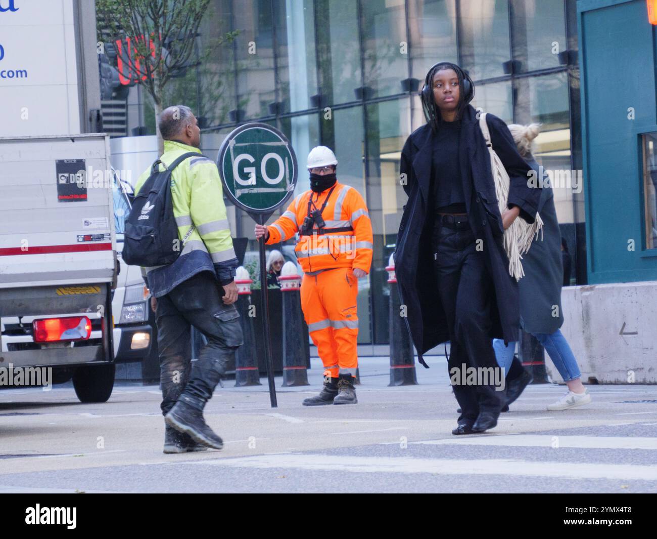 Banksman with go traffic sign directing pedestrians and traffic at ...
