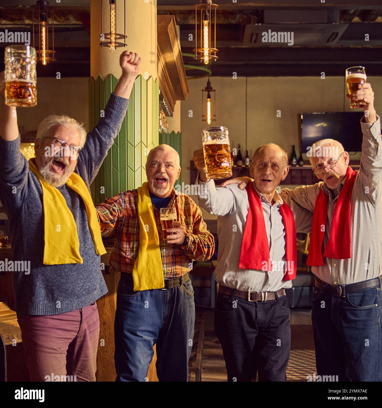 Happy elderly men, soccer fans in yellow and red scarves, raising hands ...
