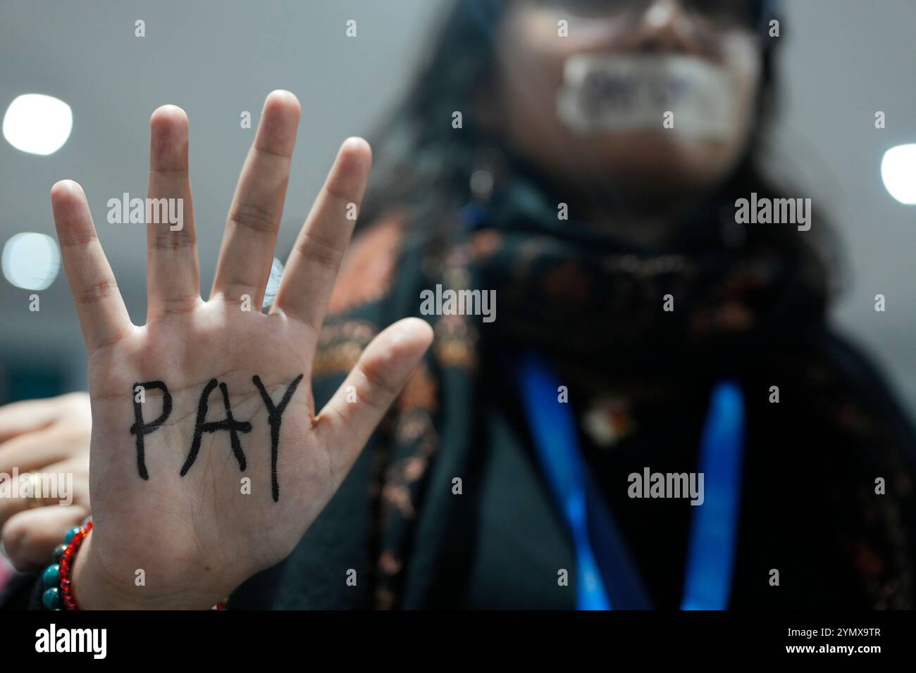 An activist displays "pay" on their hand as they participate in a ...