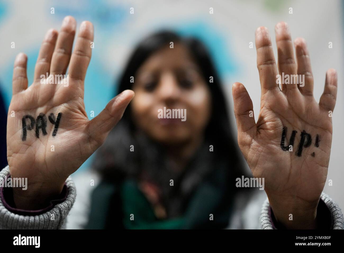 A demonstrator displays hands that reads "pay up" during a protest for ...