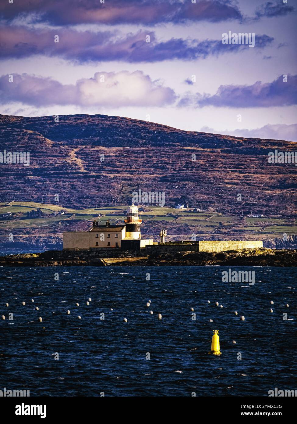 A white lighthouse with a red roof is situated on a small island ...
