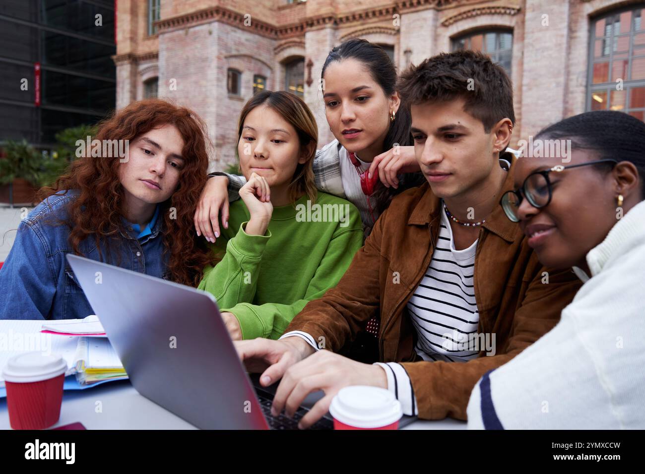 Multiracial students gathered together studying at university campus ...
