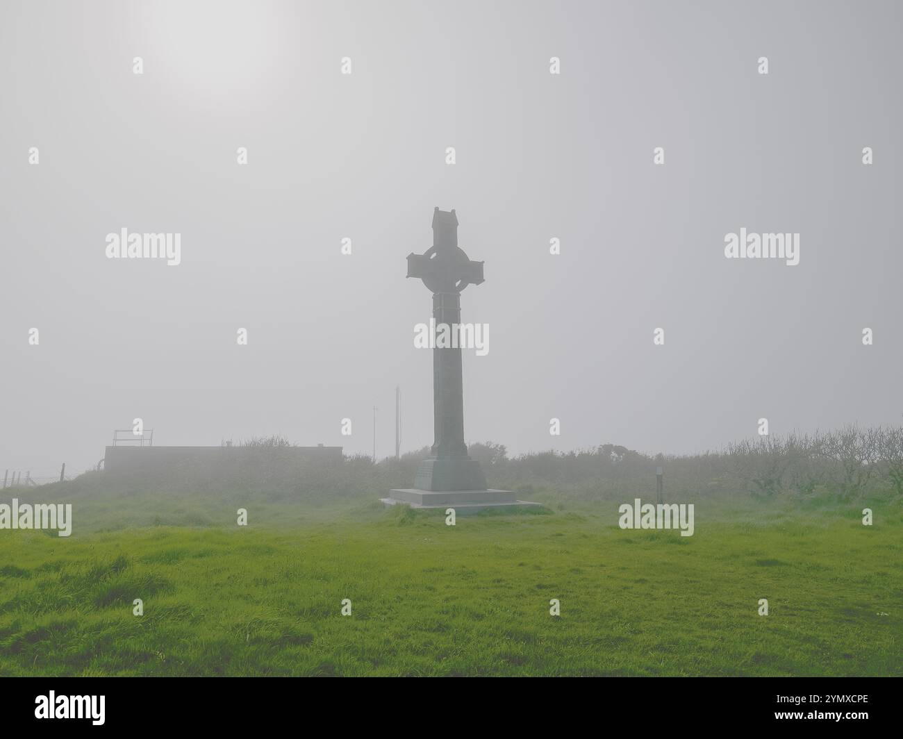 A tall Celtic cross is prominently displayed in a lush green field ...