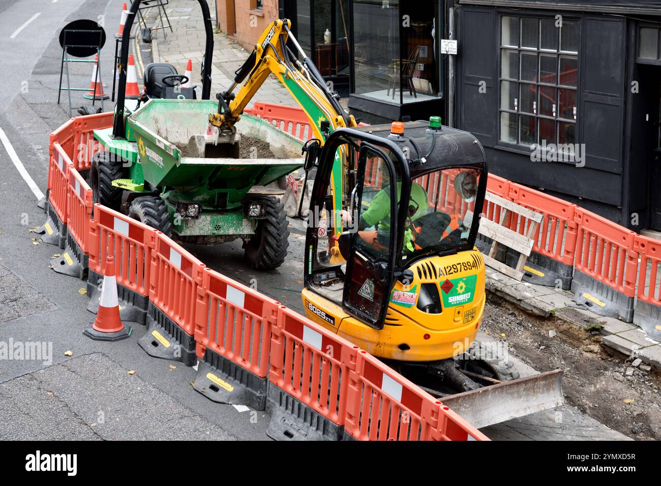 Roadworks with mini digger collecting gravel from tipper truck Stock ...