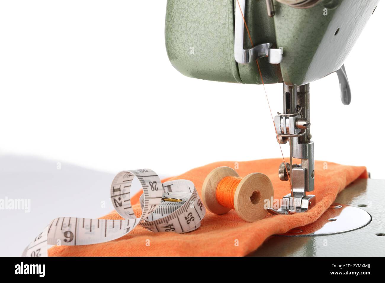 Sewing machine with orange fabric, measuring tape and spool of thread ...