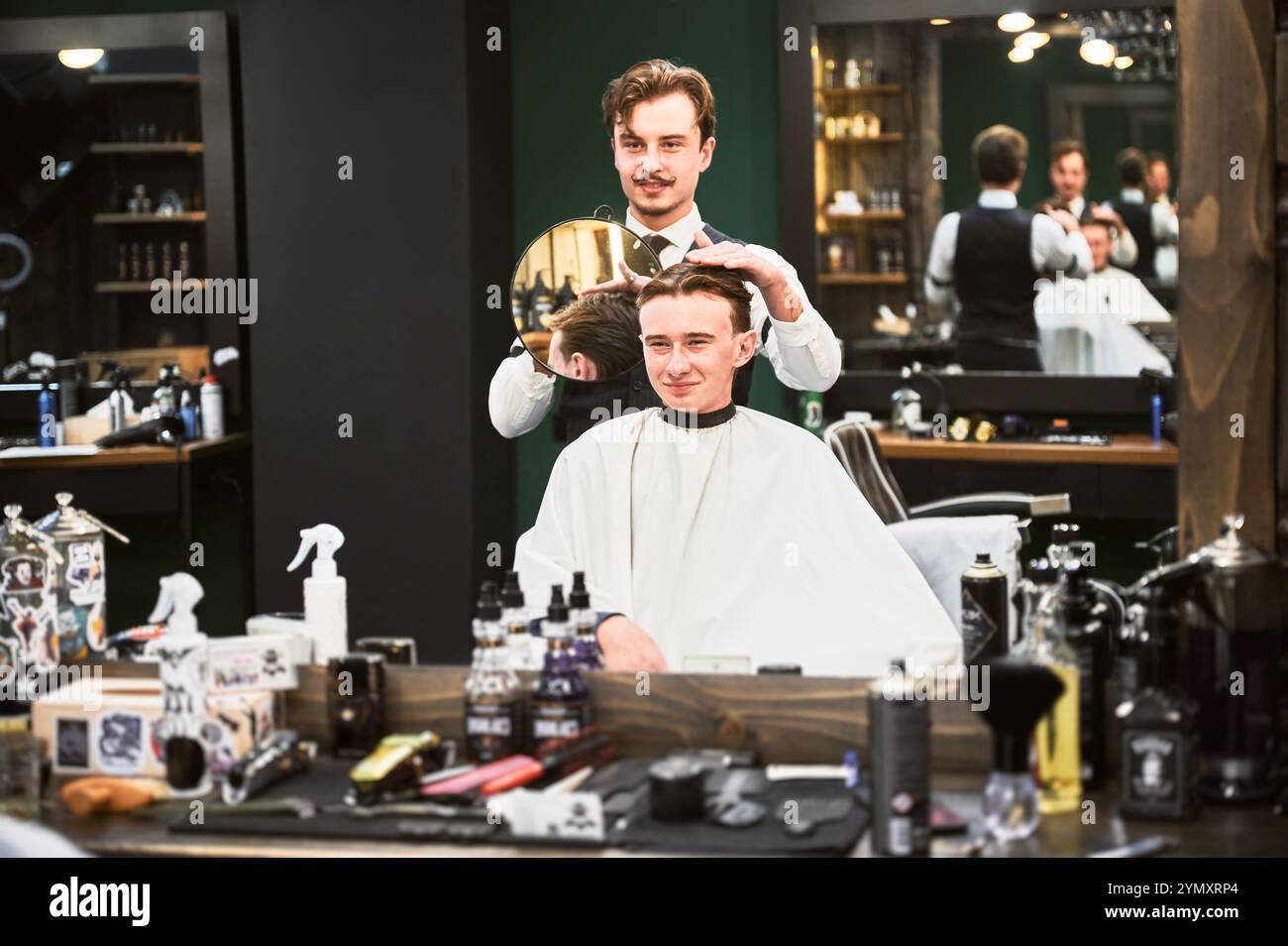 Happy hairdresser showing new haircut to his client. Barber using round ...