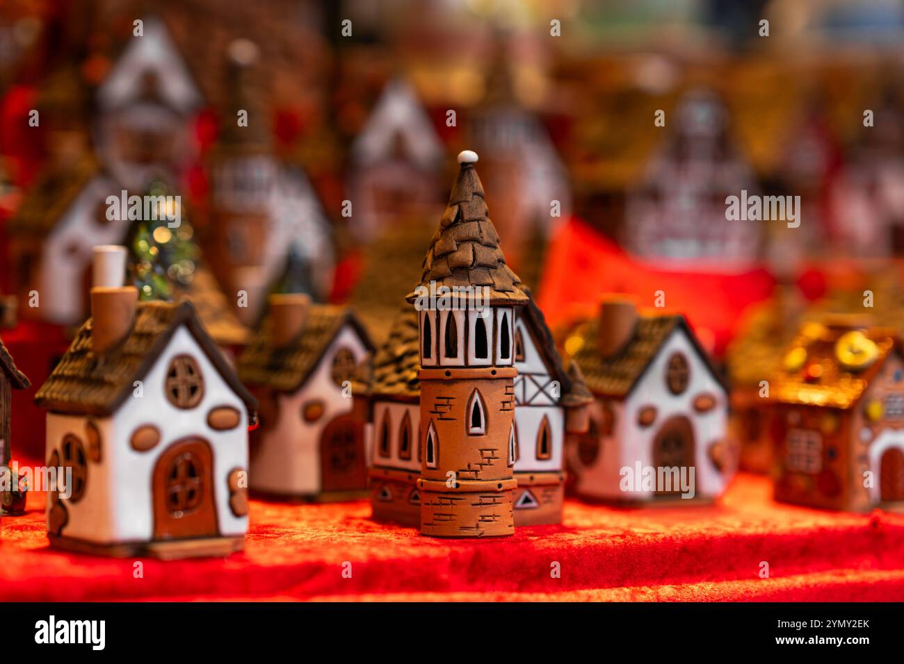 Detailed ceramic miniature houses and tower, arranged on red cloth ...