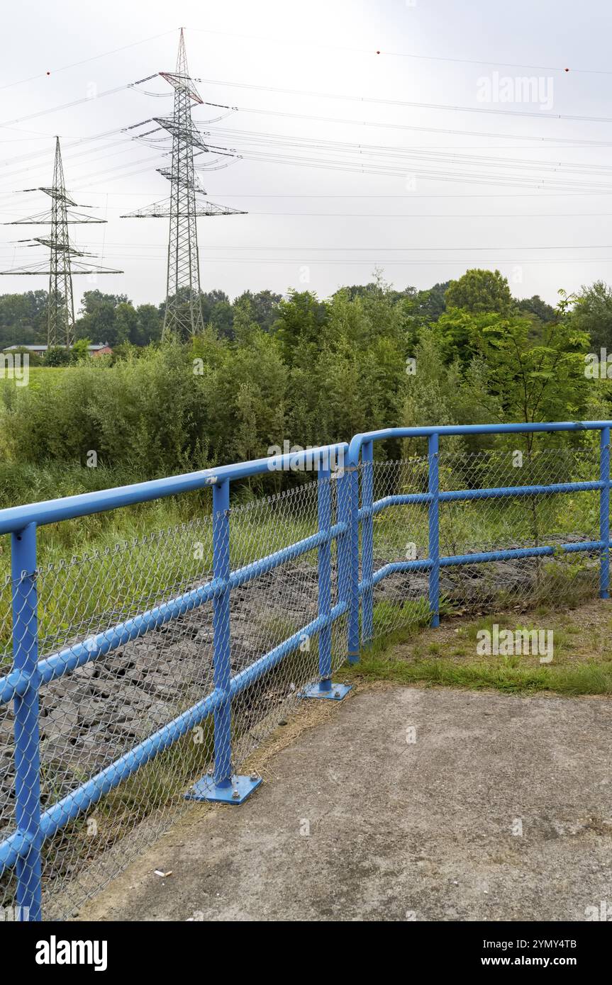 Blue metal railing in front of high voltage pylons Stock Photo - Alamy