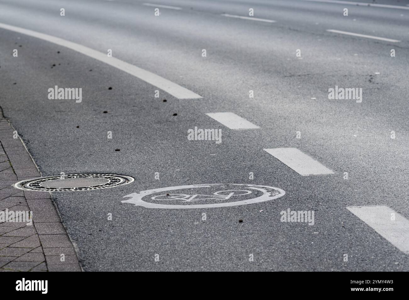 Empty road with cycle path and manhole cover Stock Photo - Alamy