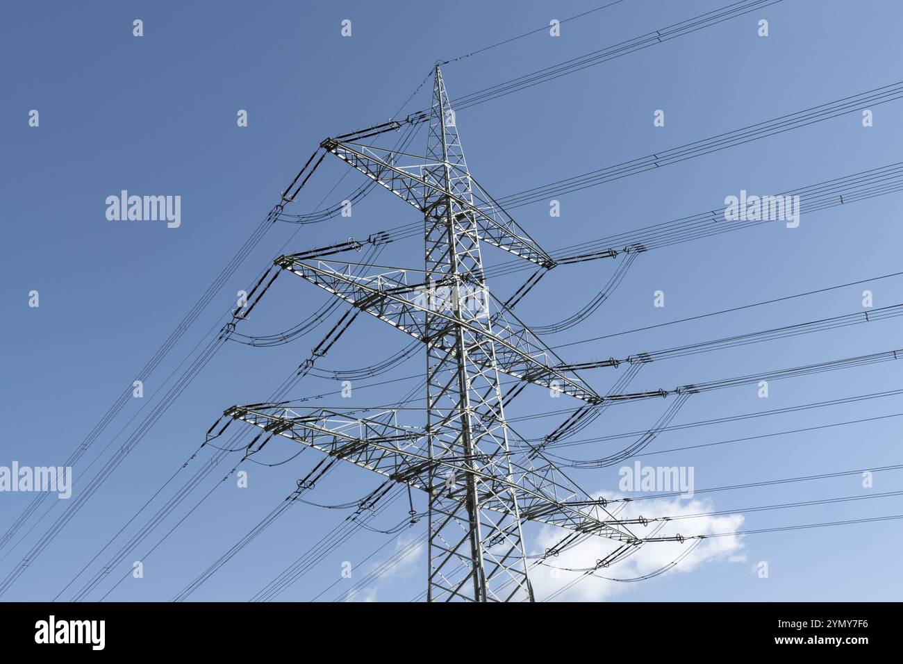 Large high voltage pylon in front of a blue sky Stock Photo - Alamy