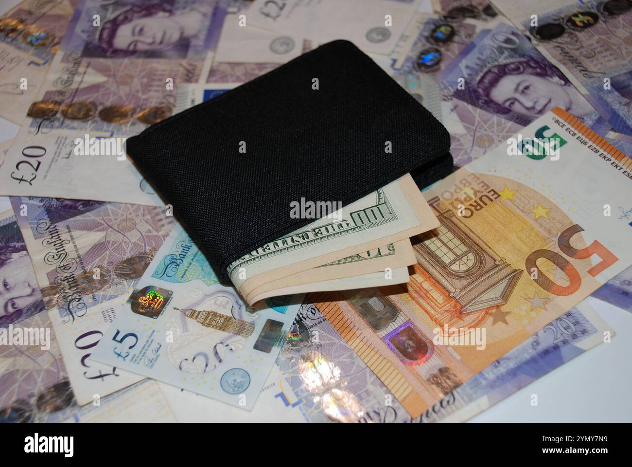 A black wallet stuffed with us dollar and euro bills is placed on ...