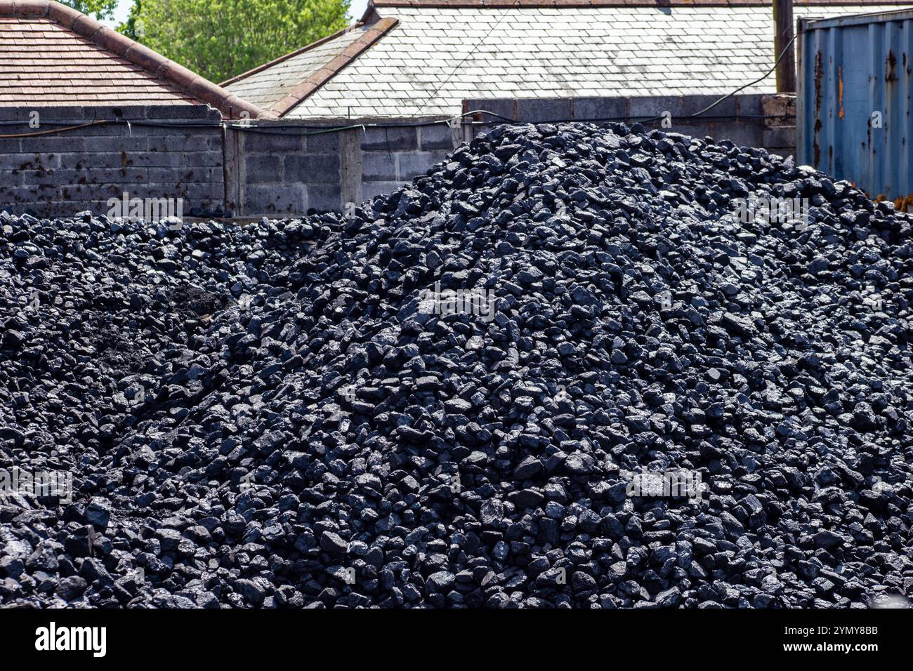 Large pile of black coal in an outdoor yard surrounded by industrial ...