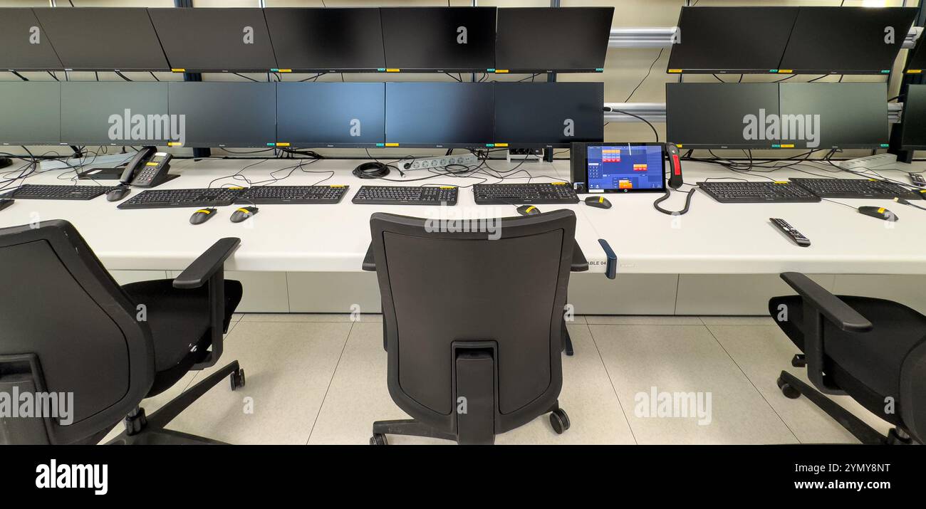 A white desk with multiple monitors and keyboards sits empty in a ...